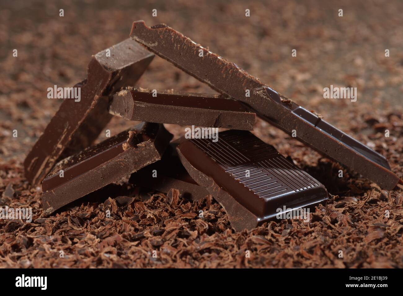 Broken dark chocolate bar and chocolate flakes on black kitchen table ...