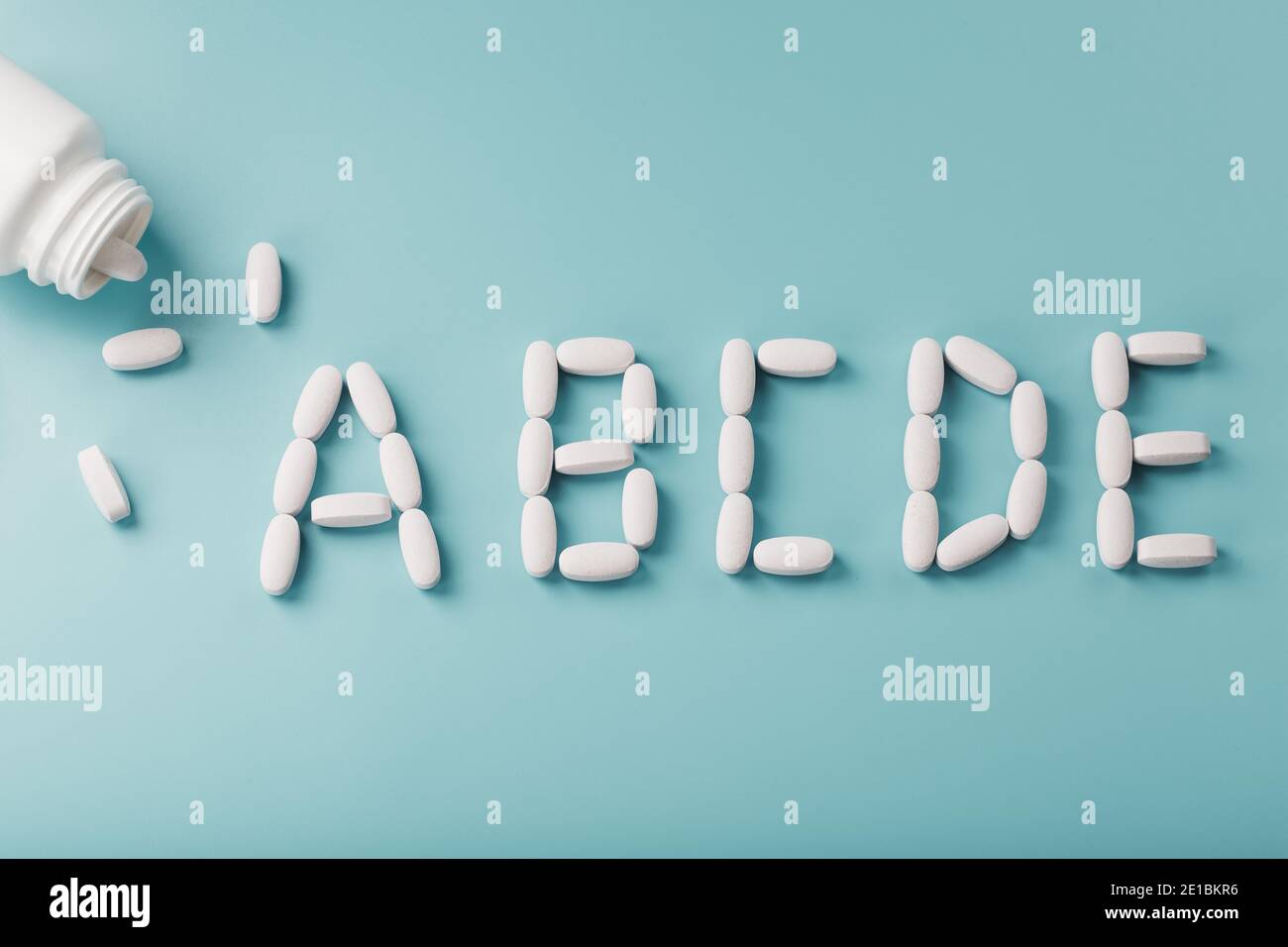 Pour the letter of vitamin A B C D E in capsules from a jar on a blue ...