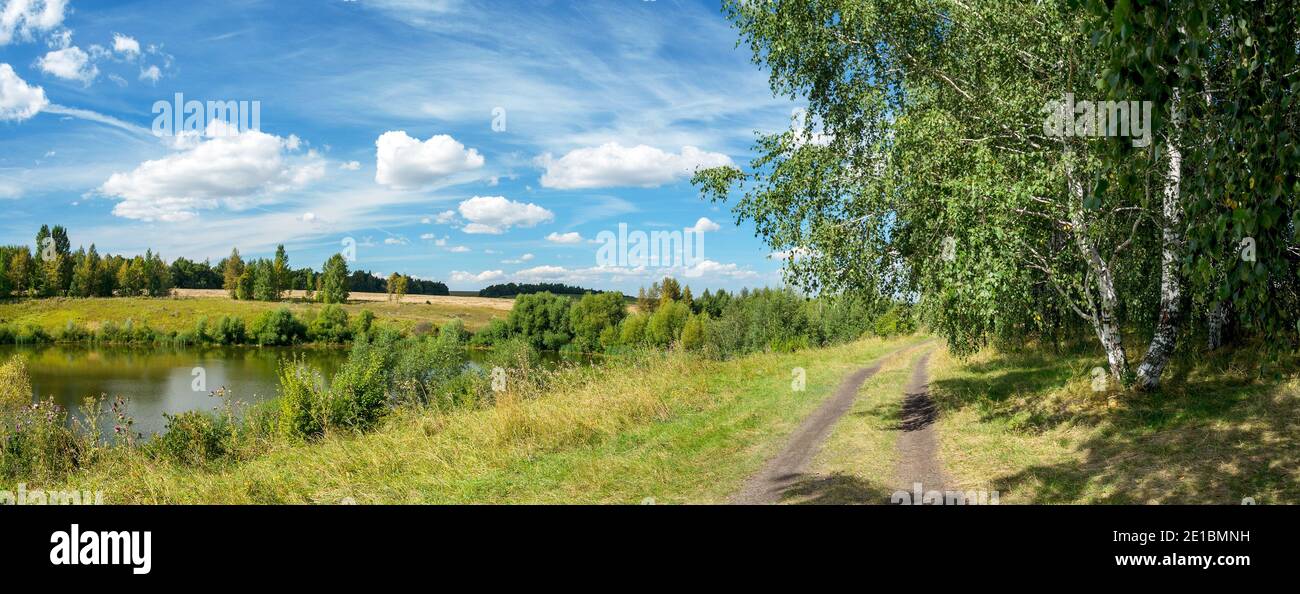 Sunny summer rural landscape with calm river, birch trees near country ...