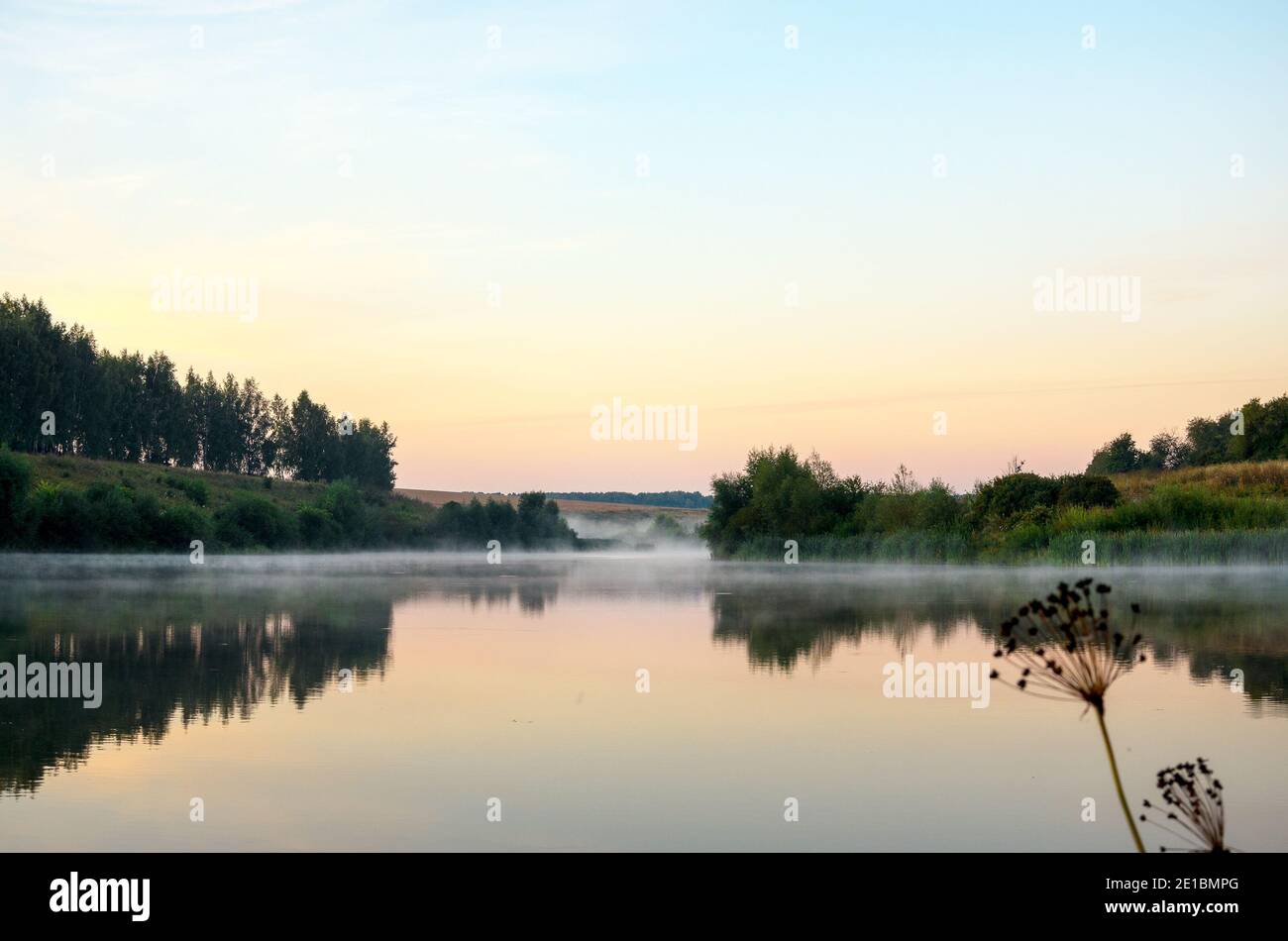 Panoramic view of calm lake during foggy sunrise Stock Photo - Alamy