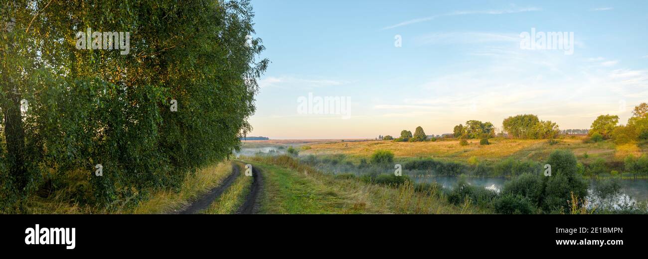 Tranquil summer rural landscape with calm river,country road and farm ...