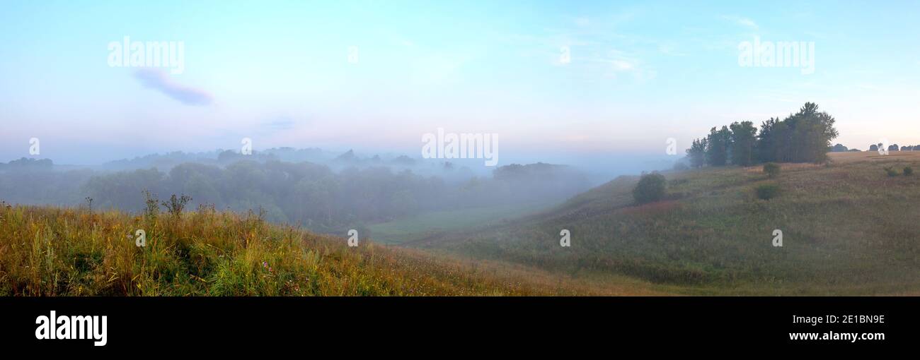 Beautiful summer hazy landscape with foggy hollow and green hills ...