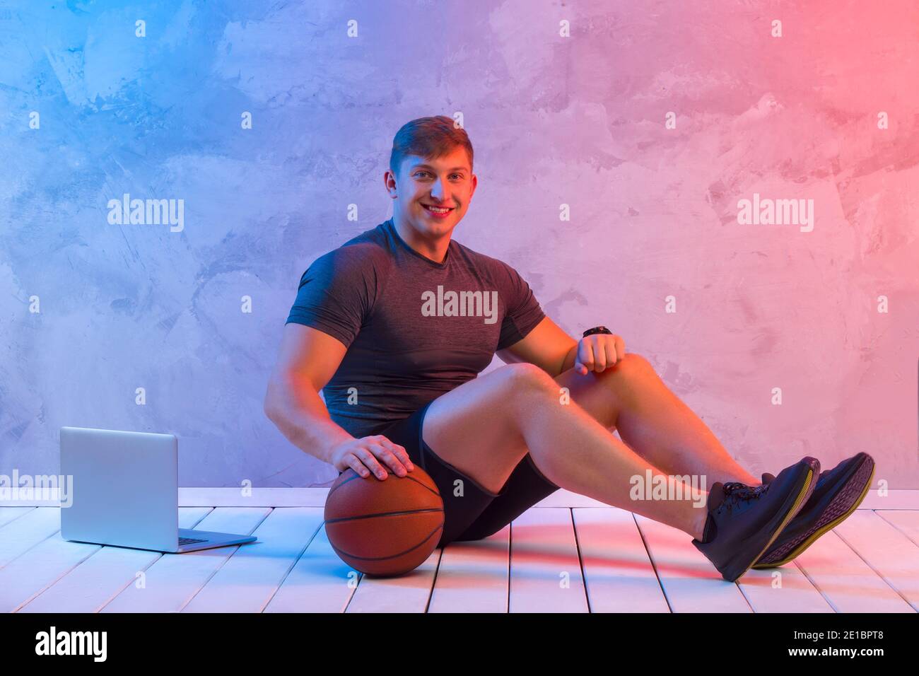 Man doing exercises with basketball ball watching online tutorials on ...
