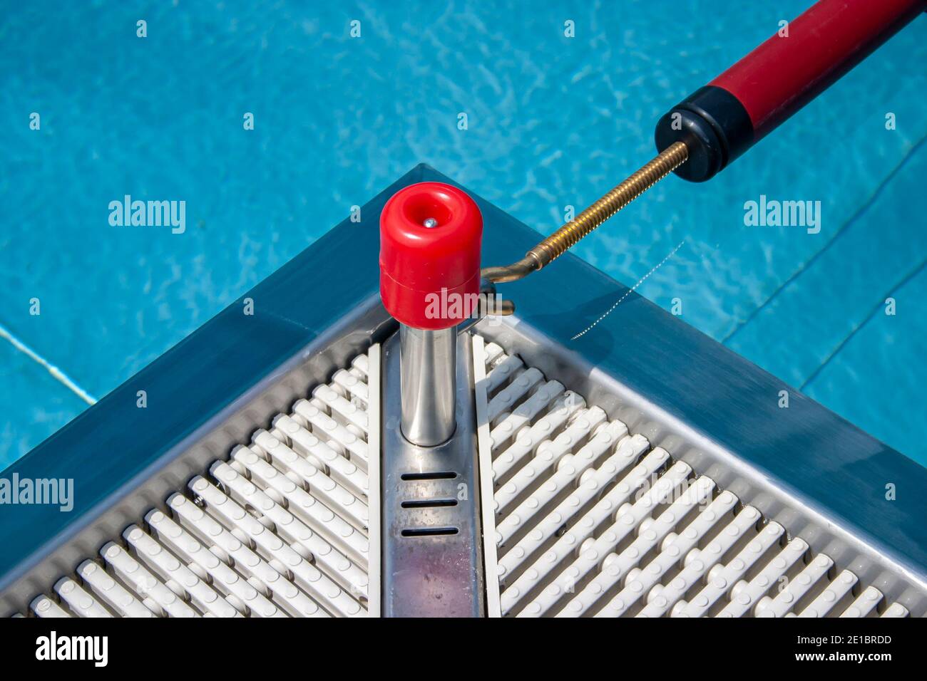 detail of a corner of a swimming pool with blue water and red bracket ...