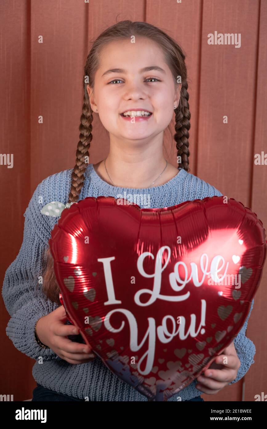 cute smiling girl holding red heart shaped balloon. Caucasian beautiful ...