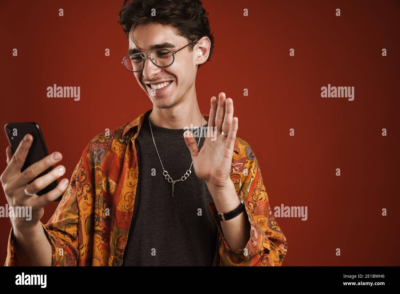 Happy young hipster man waving hello during online video call via ...