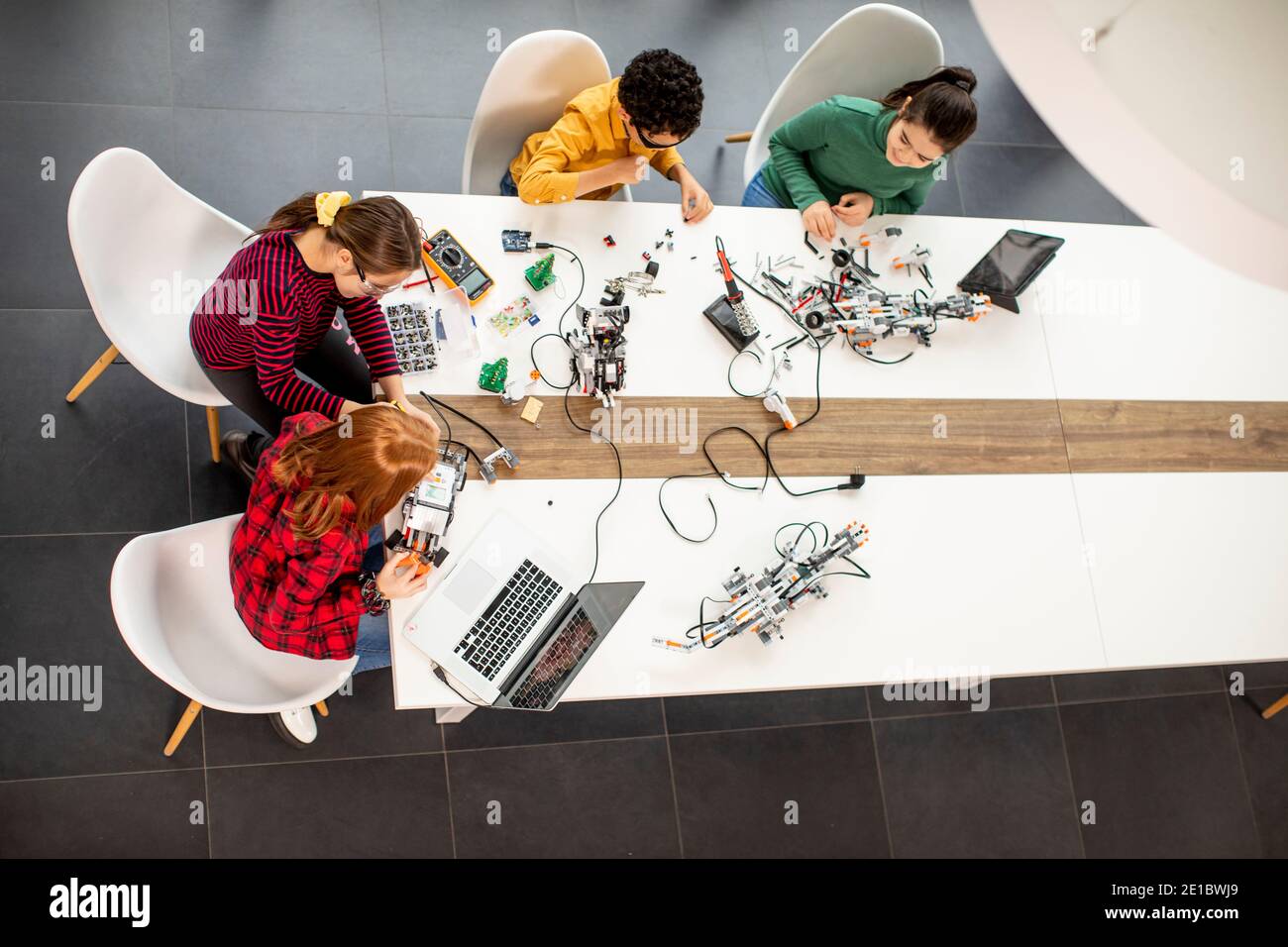 Overhead view at group of happy kids programming electric toys and ...