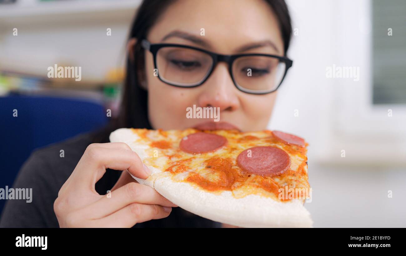 Young woman eats a pizza from delivery service while at work Stock ...