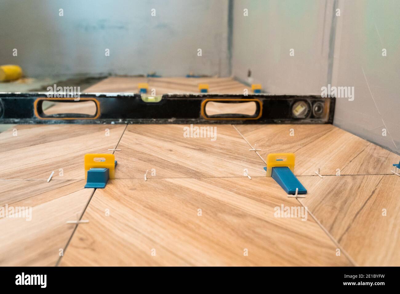 Tiling work. The man checks the level of the correct laying of the ...