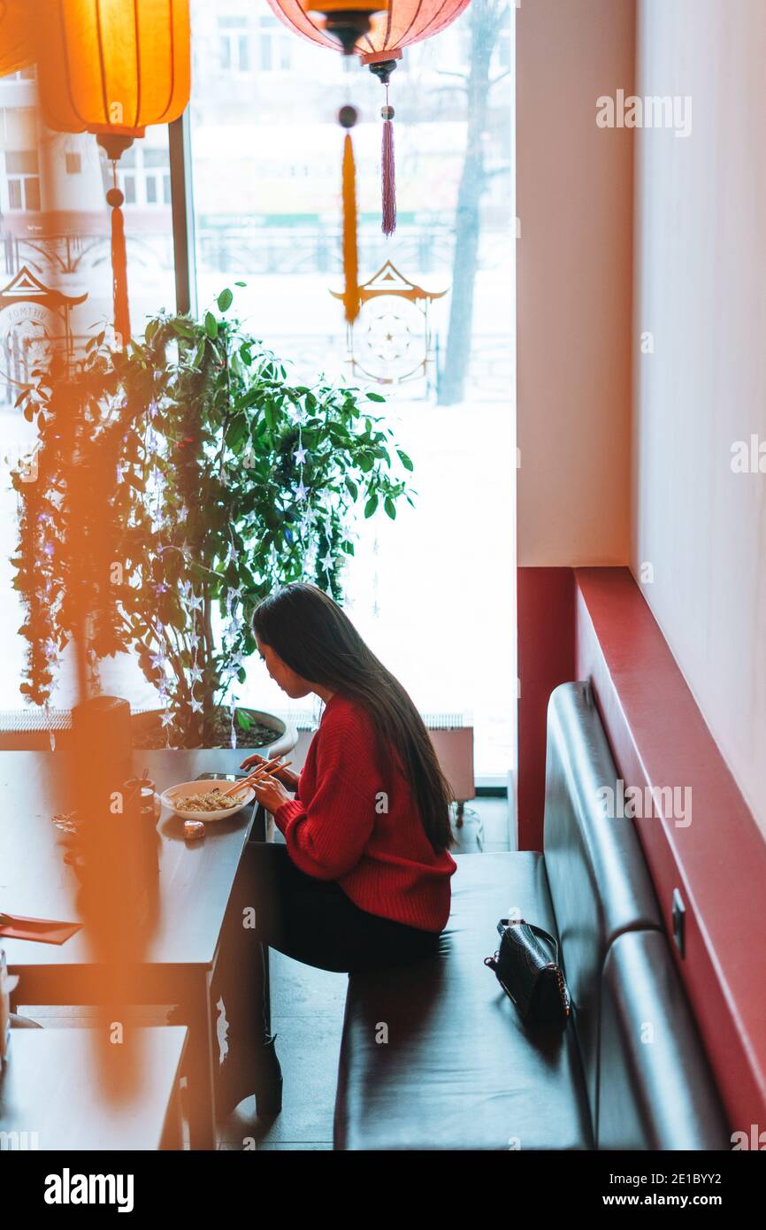 Beautiful smiling young asian woman in red clothes eating asian food ...