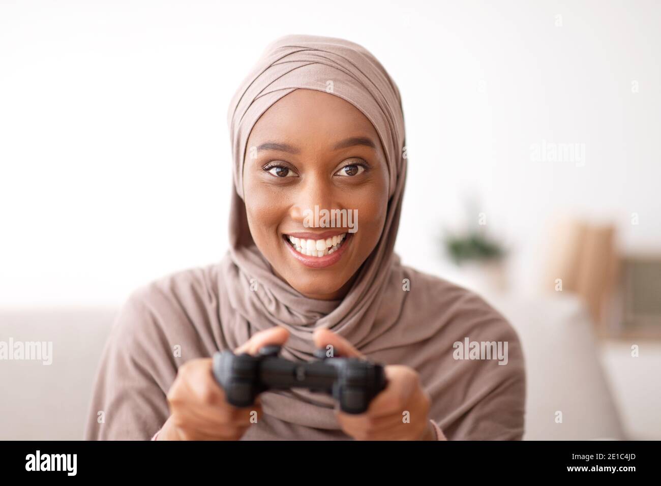 Portrait of happy Muslim woman in hijab holding joystick, playing ...