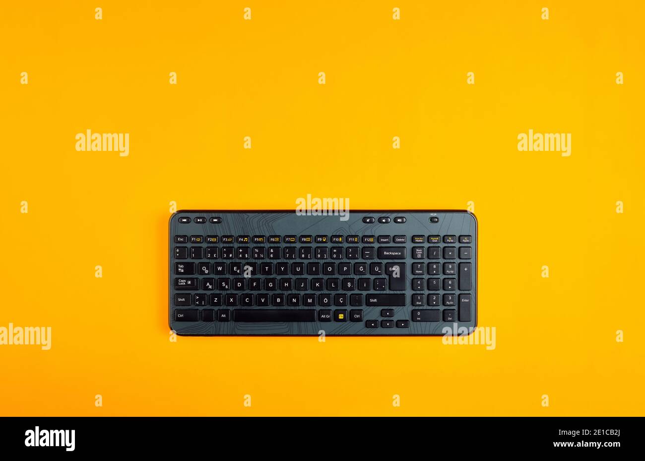 Black computer keyboard on yellow background with copy space. Overhead ...