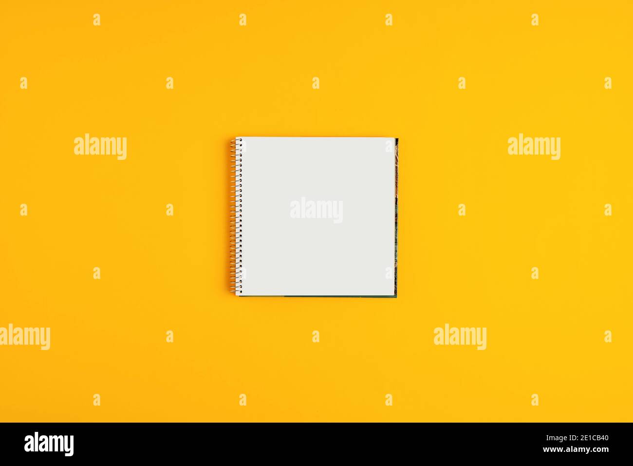 Blank spiral notepad or notebook in square shape on yellow background ...