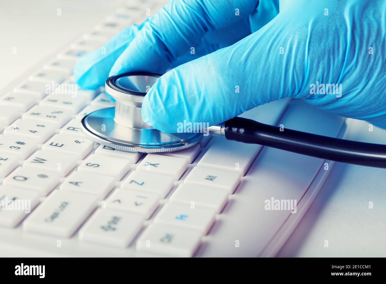 Hand with medical glove holding a stethoscope on computer keyboard ...
