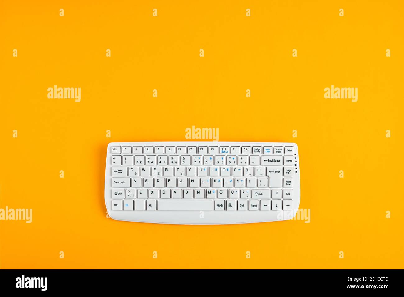 White computer keyboard on yellow background with copy space. Overhead ...