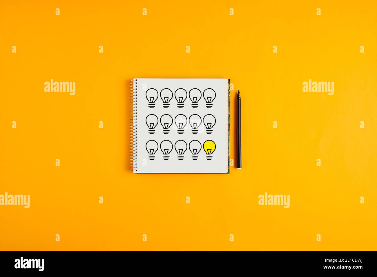Light bulbs drawn on a notepad with black pen next to it against yellow ...