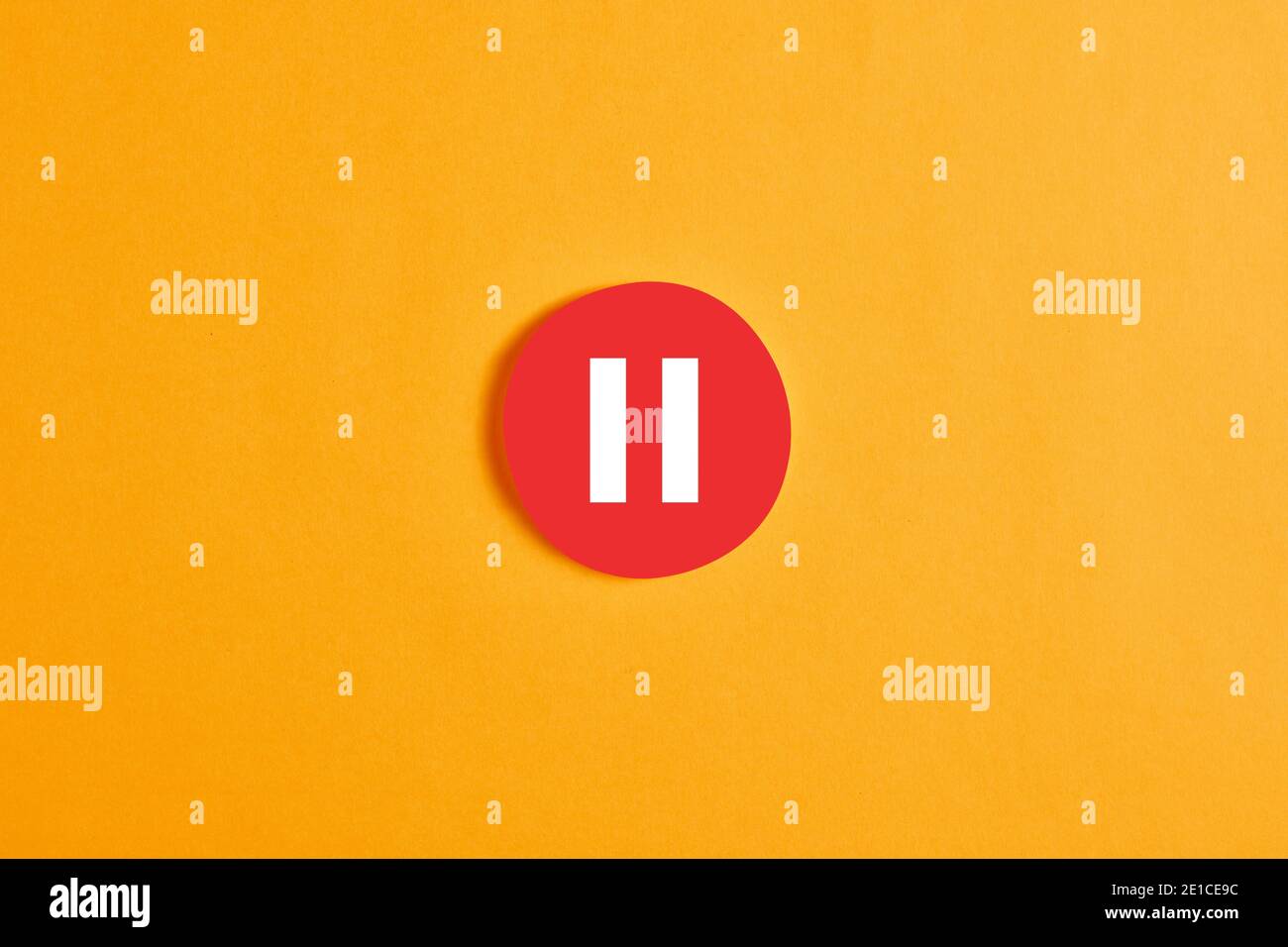 Red round circle with a pause button or icon against yellow background ...