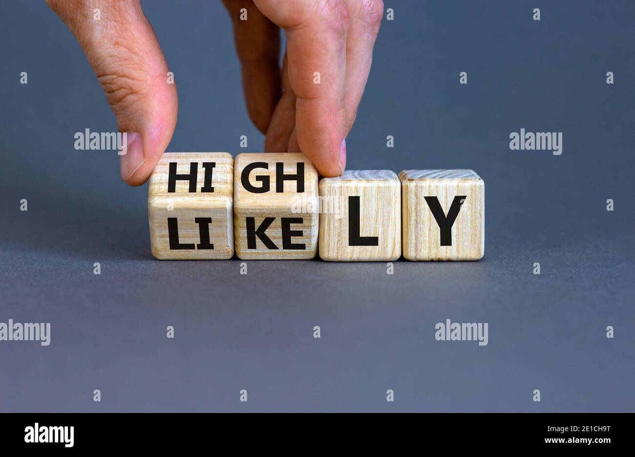 Highly likely symbol. Hand turns the wooden cube with words 'Highly ...