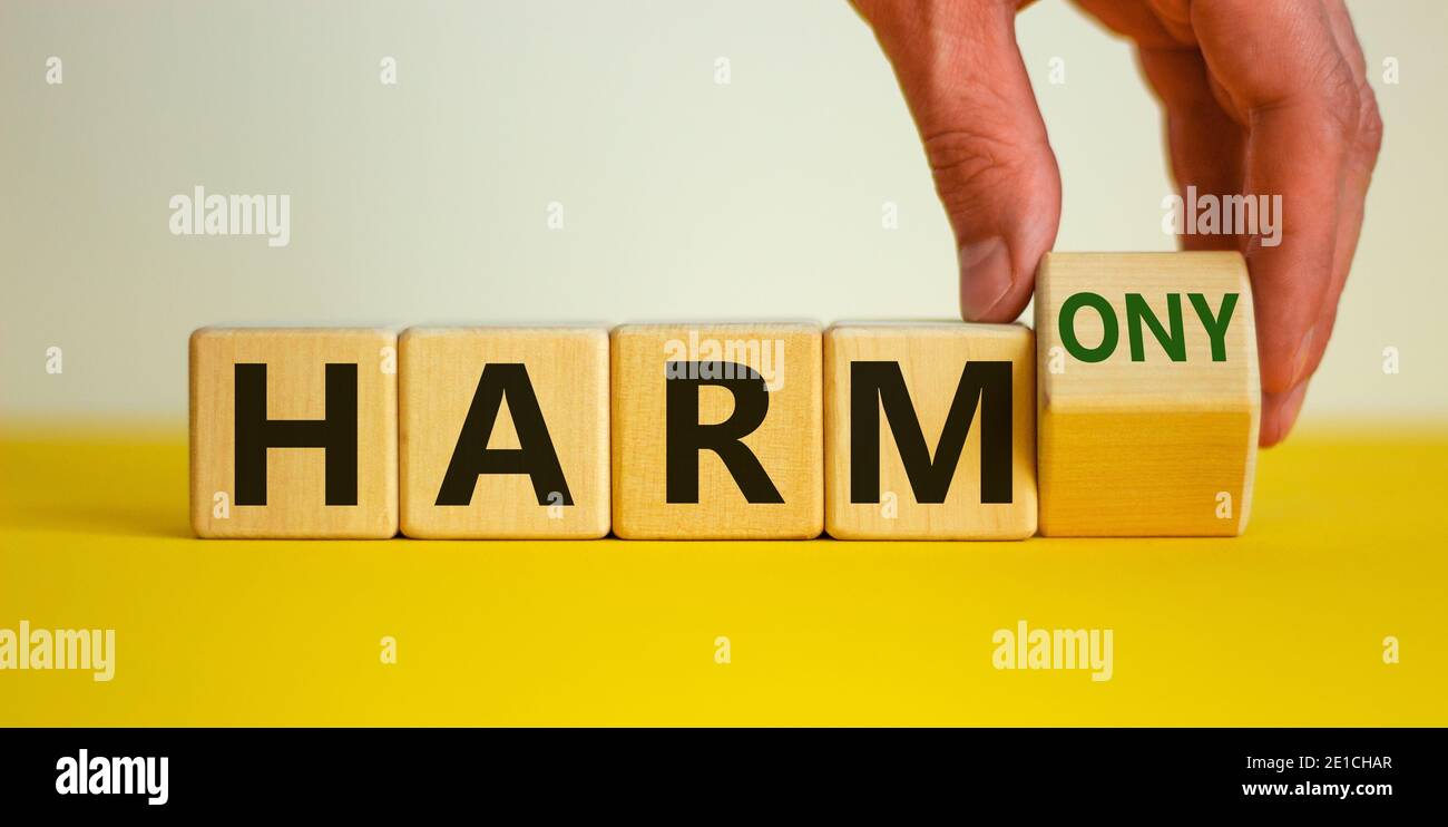 From harm to harmony. Male hand turns the cube and changes word 'harm ...