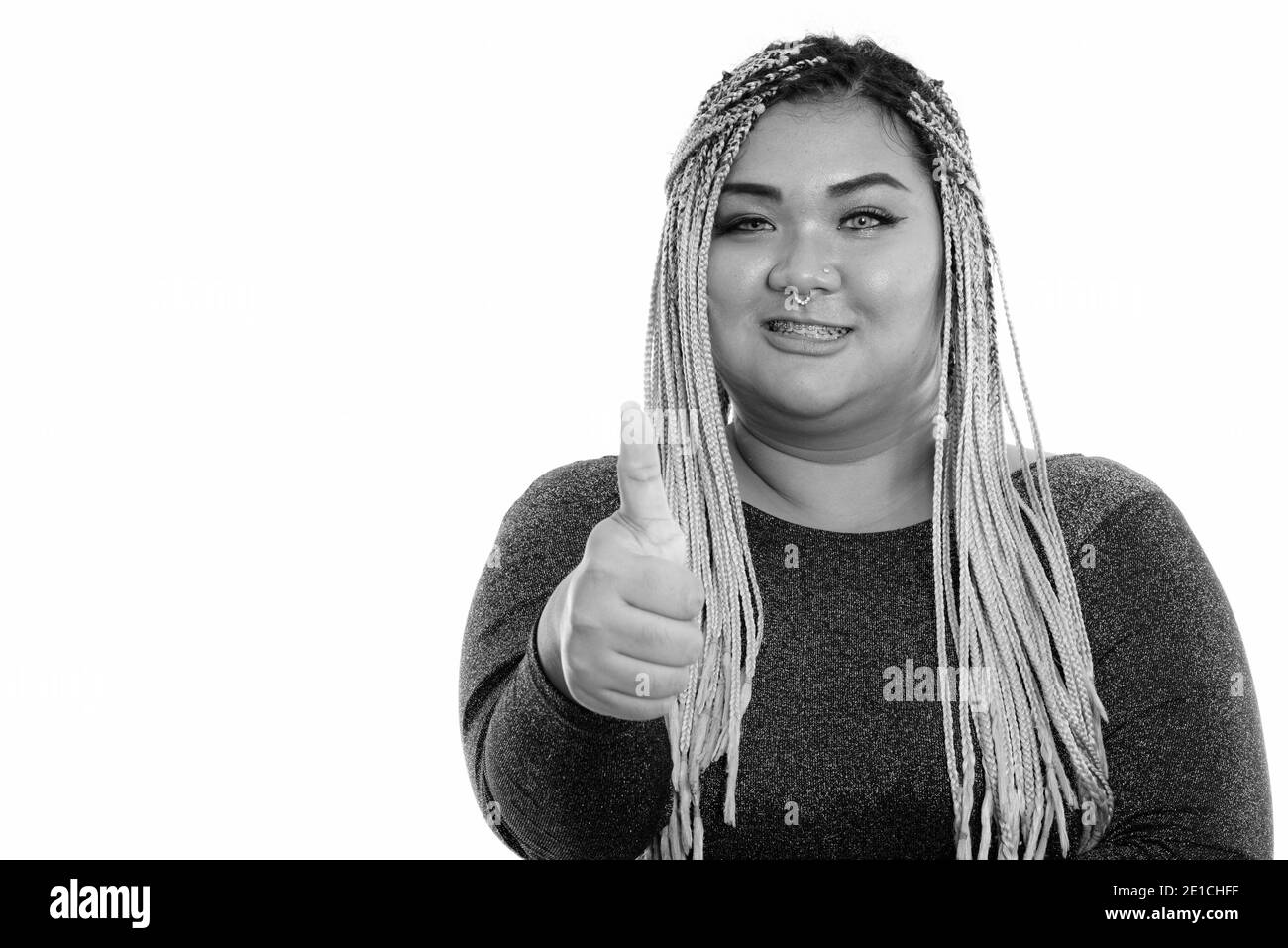 Studio shot of young happy fat Asian woman smiling while giving thumb ...