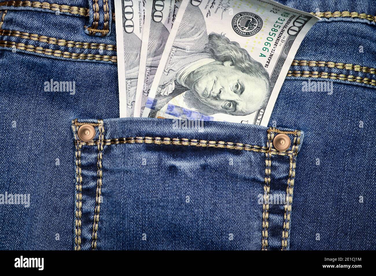 A stack of American hundred dollar bills in the back pocket of blue ...