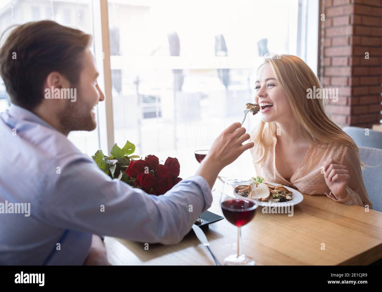Lovely young couple having romantic dinner with flowers and wine at ...
