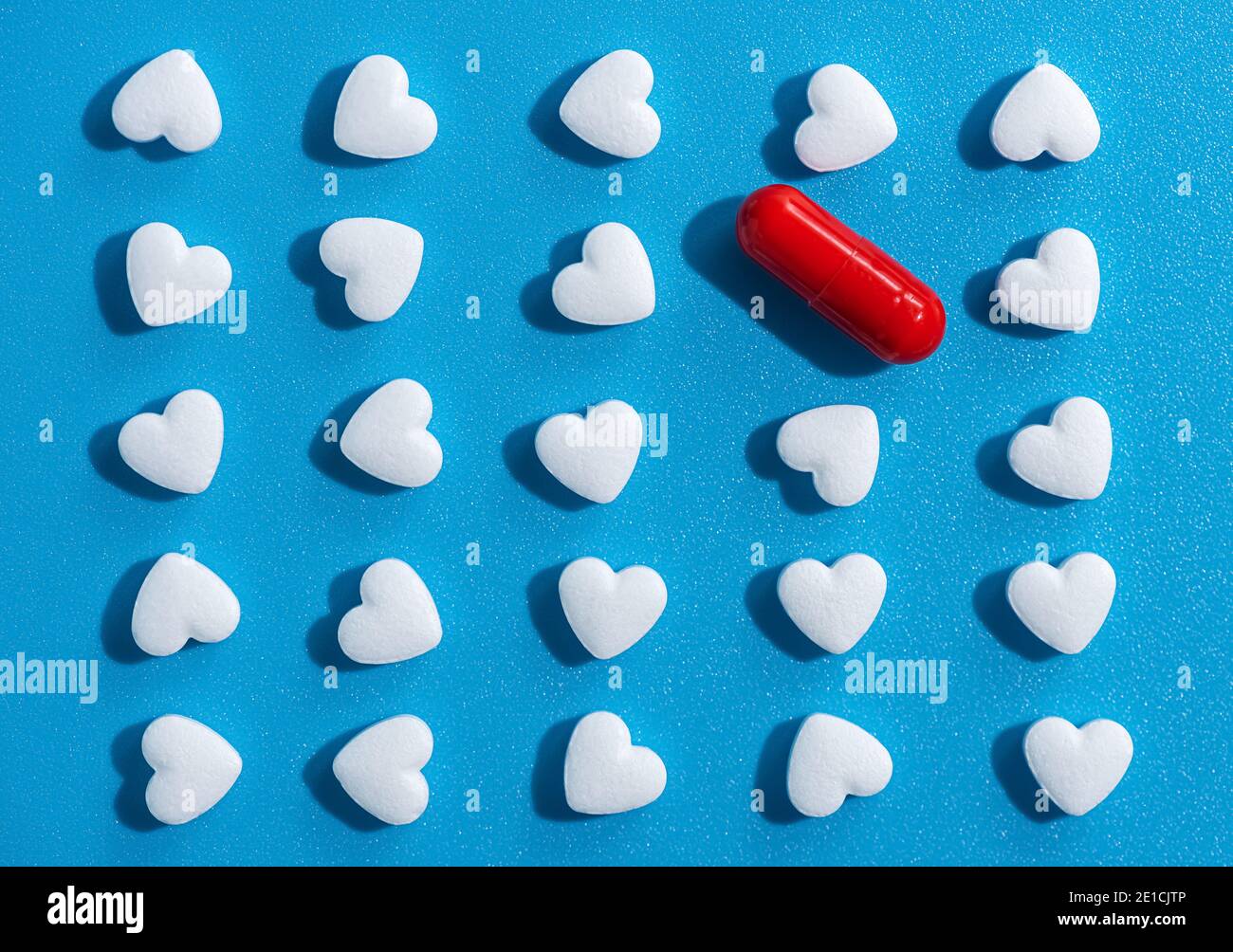 heart-shaped tablets and red pill. pattern on blue background. medicine ...