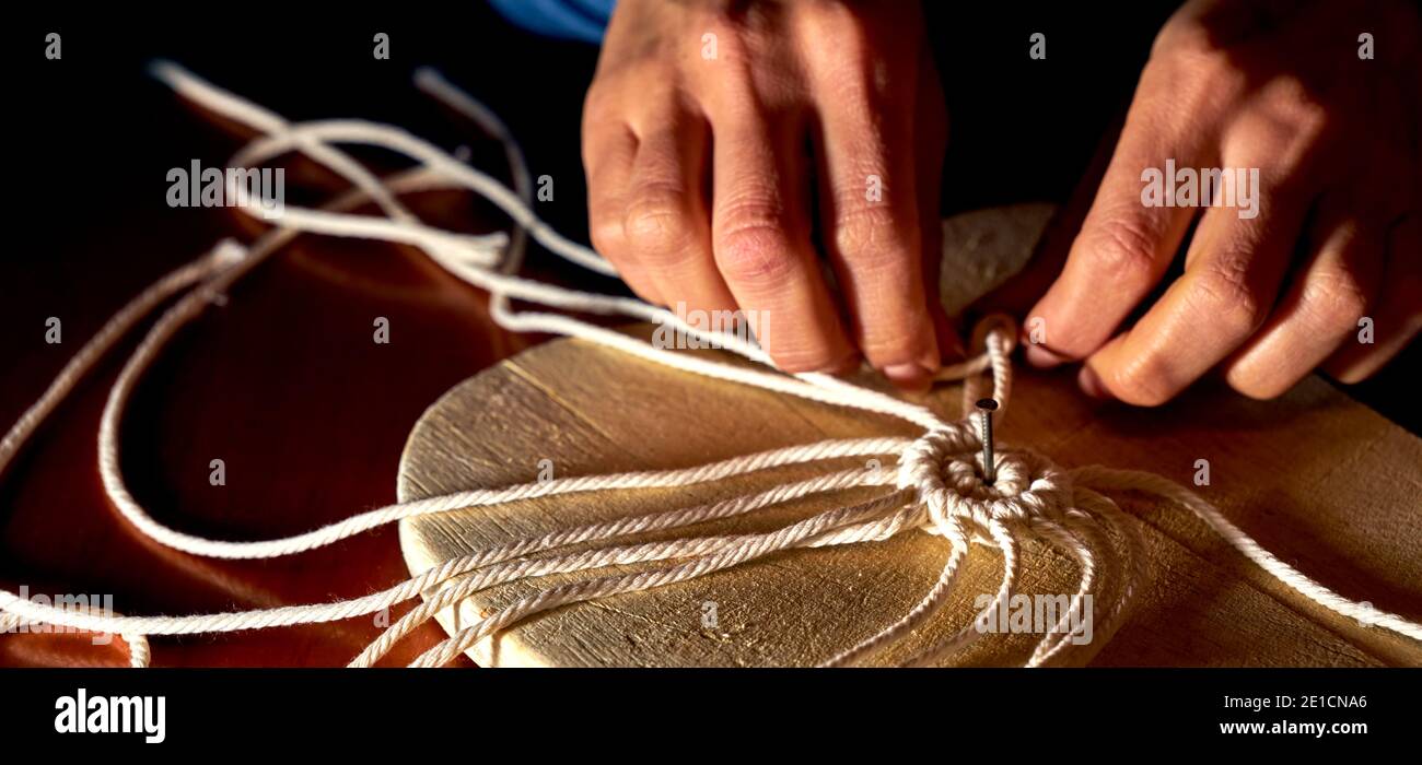First knots to make a macrame coaster from a rope on a plate of wood ...