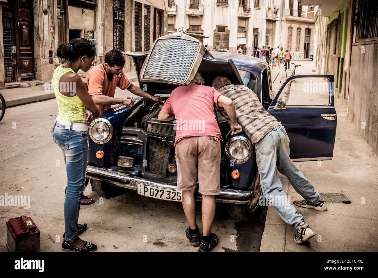 Group of people help repair classic old car on the streets of Havana ...