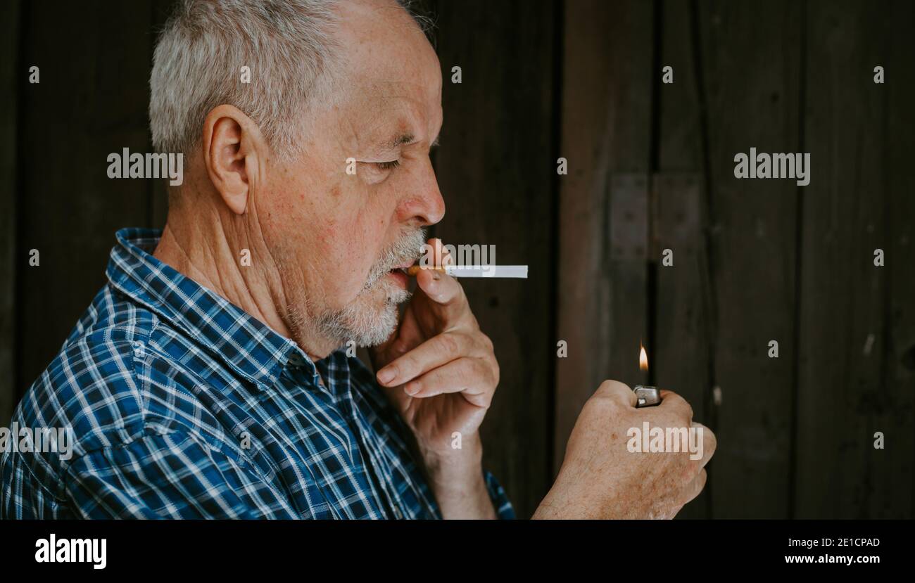 An old senior man smoking a cigarette outside, smoke addiction, bad ...