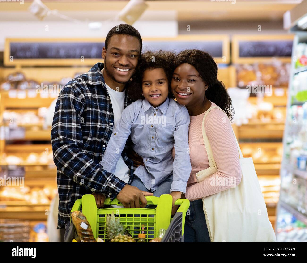 Happy black family with shopping cart purchasing food at supermarket ...