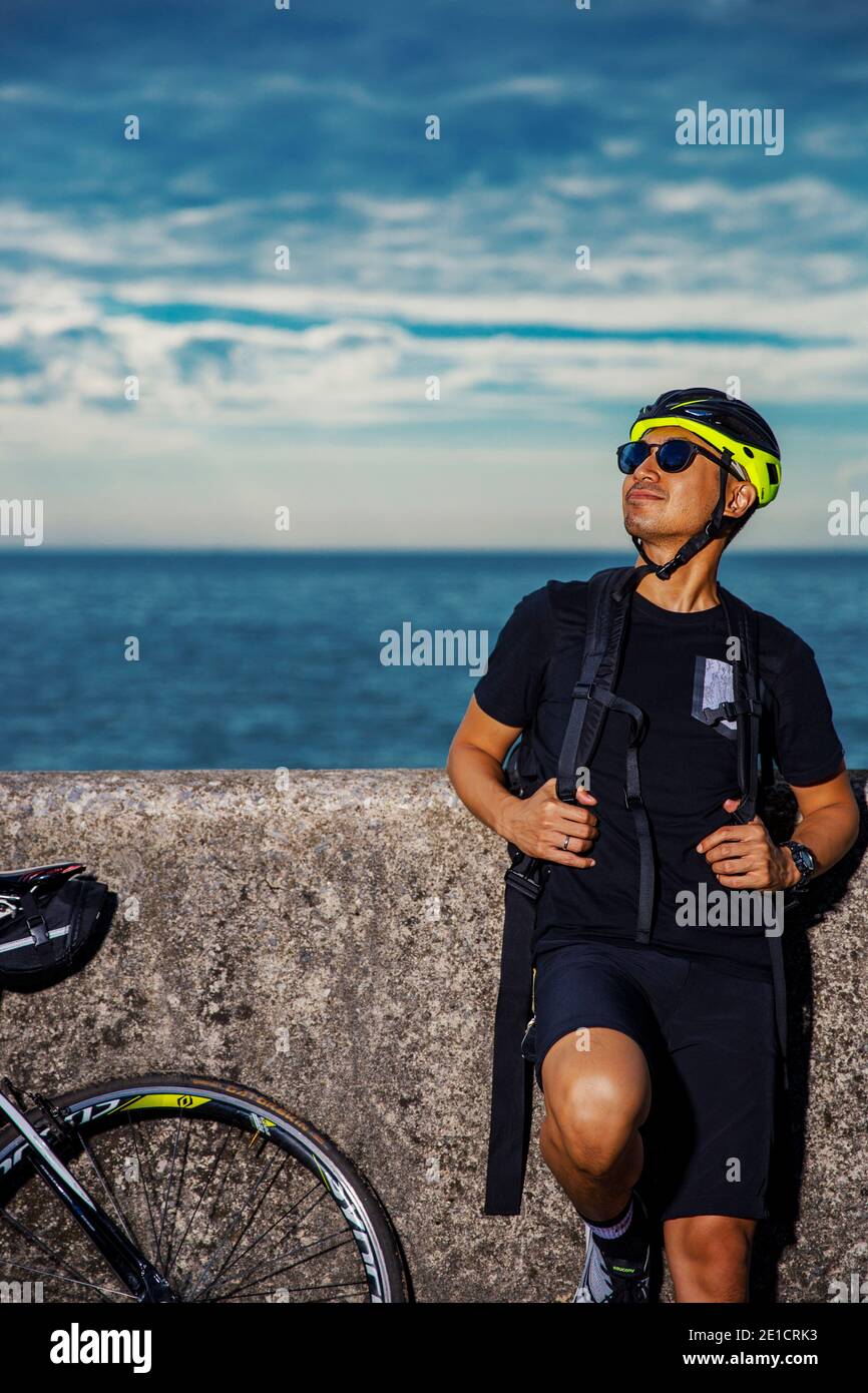 A cyclist (born Filipino) poses for a photograph leaning against a ...