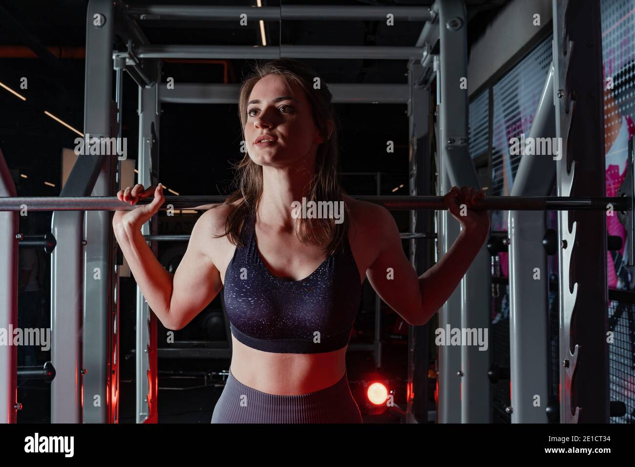 Beautiful young fitness woman doing squats with a barbell on the Smith ...