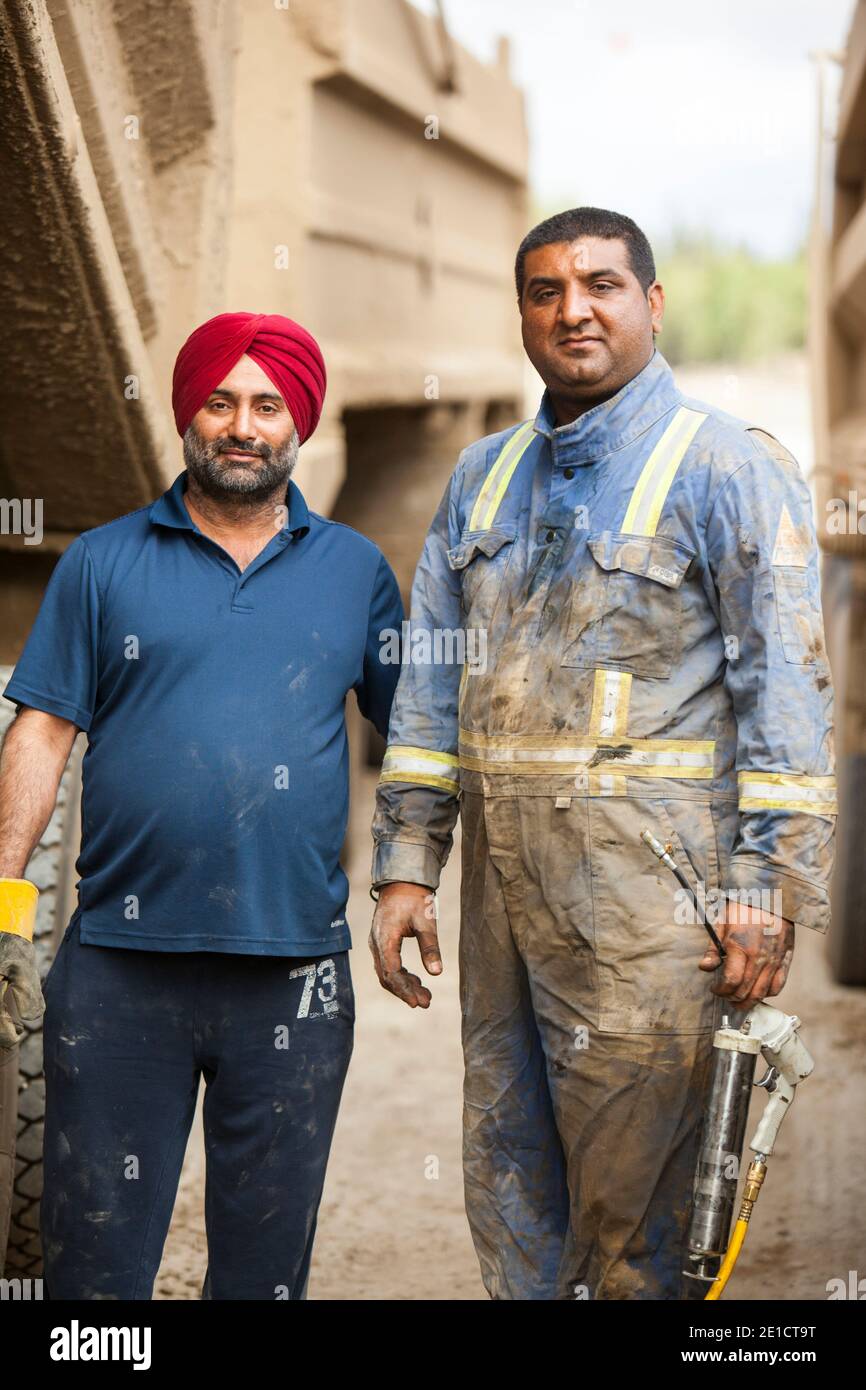 Tar sands workers working on trucks at a mine north of Fort McMurray ...