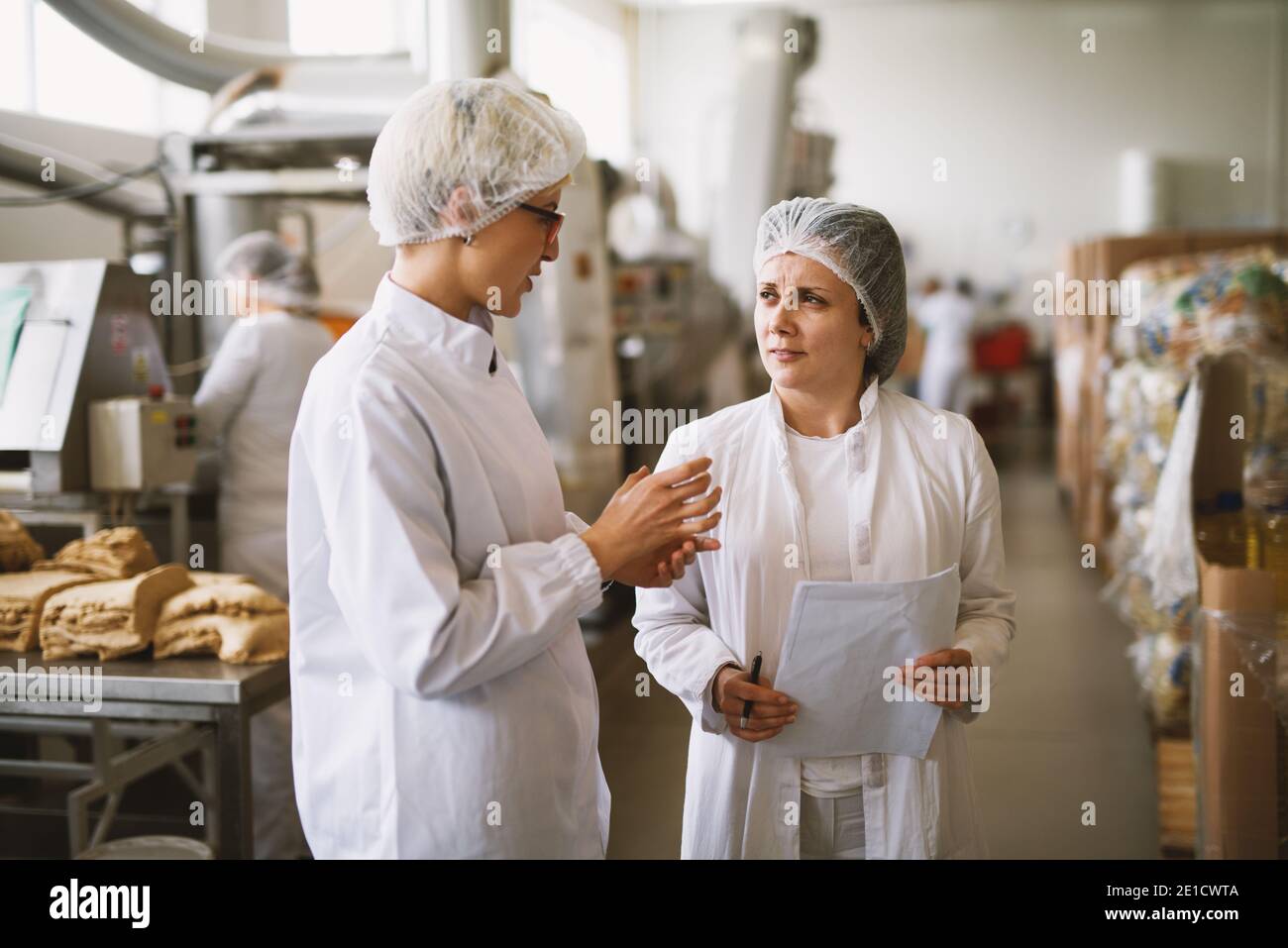 Focused dedicated female employee in sterile clothes talking about ...