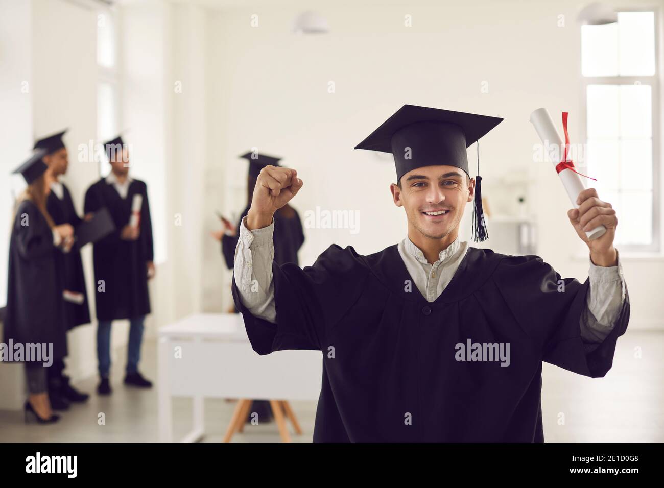 Graduate with a diploma in his hands in the office against the ...