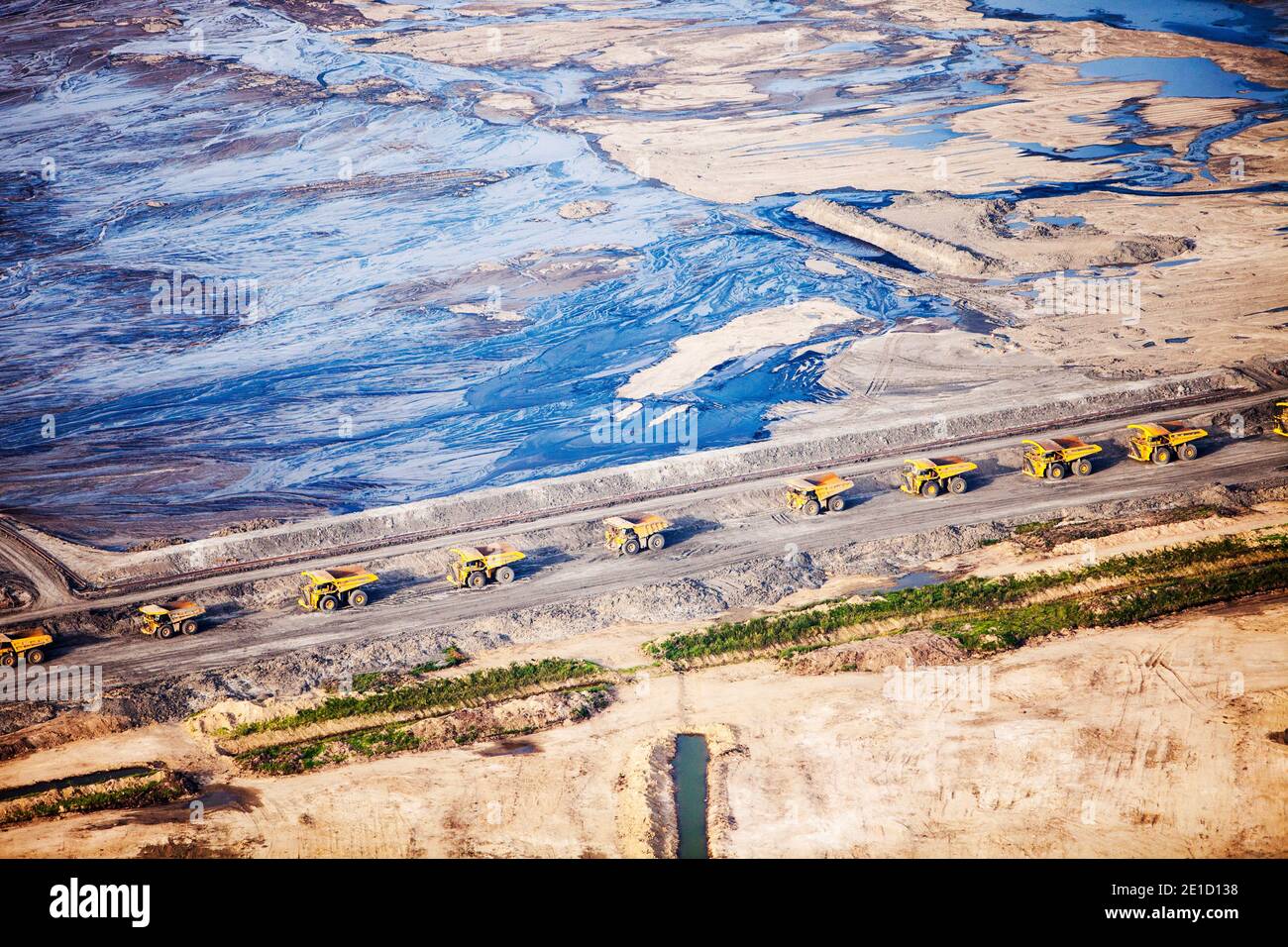 Massive dump trucks que up to load with tar sand in a mine north of ...
