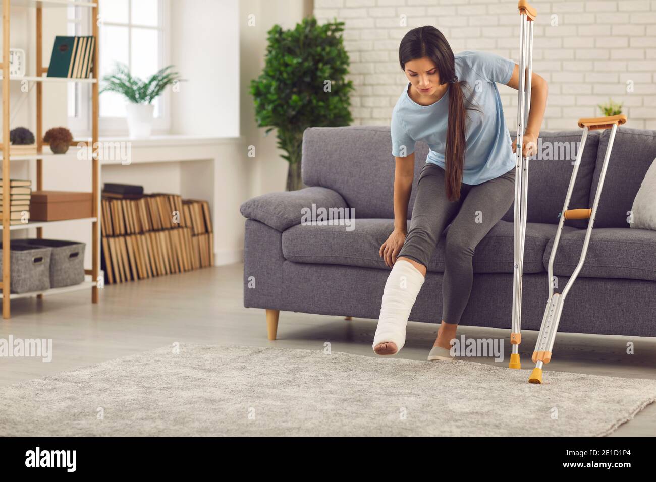 Woman with broken leg trying to stand up and walk with crutches in the ...