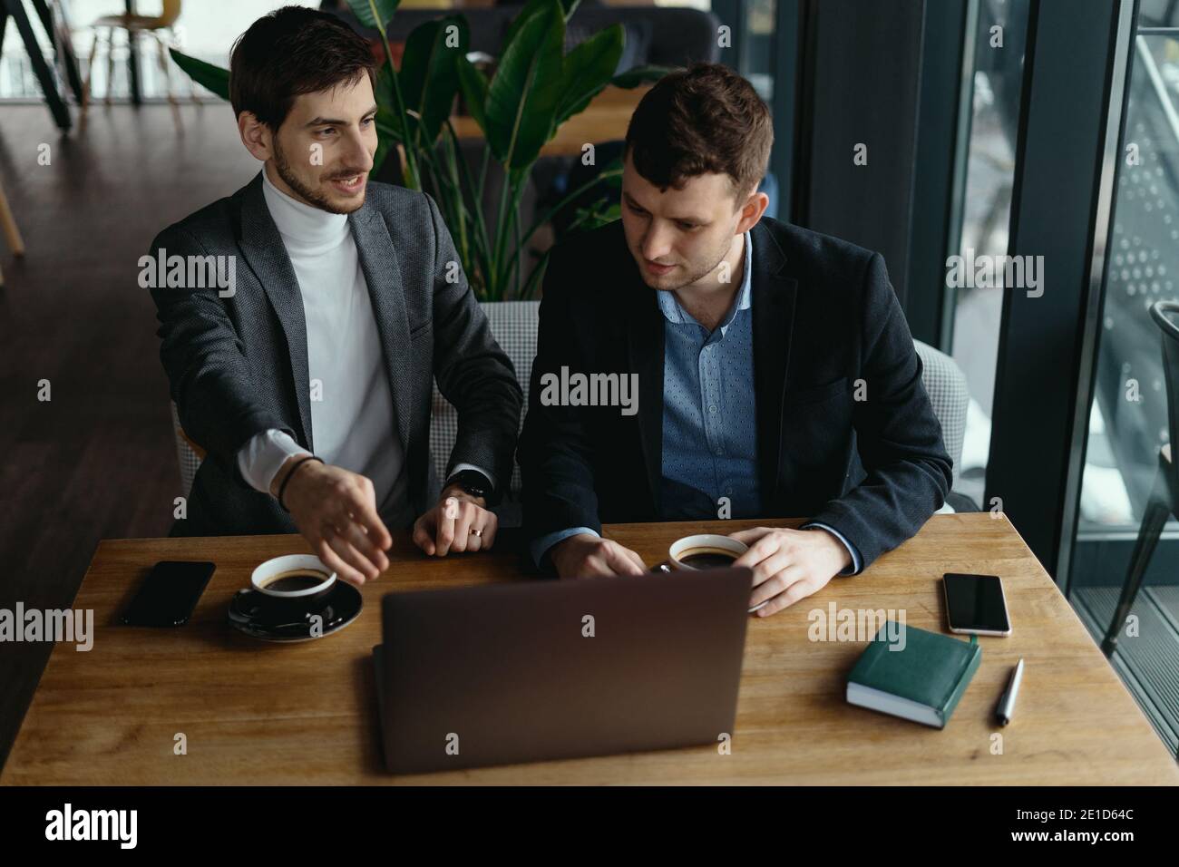 Two handsome businessmen are talking and pointing laptop screen while ...