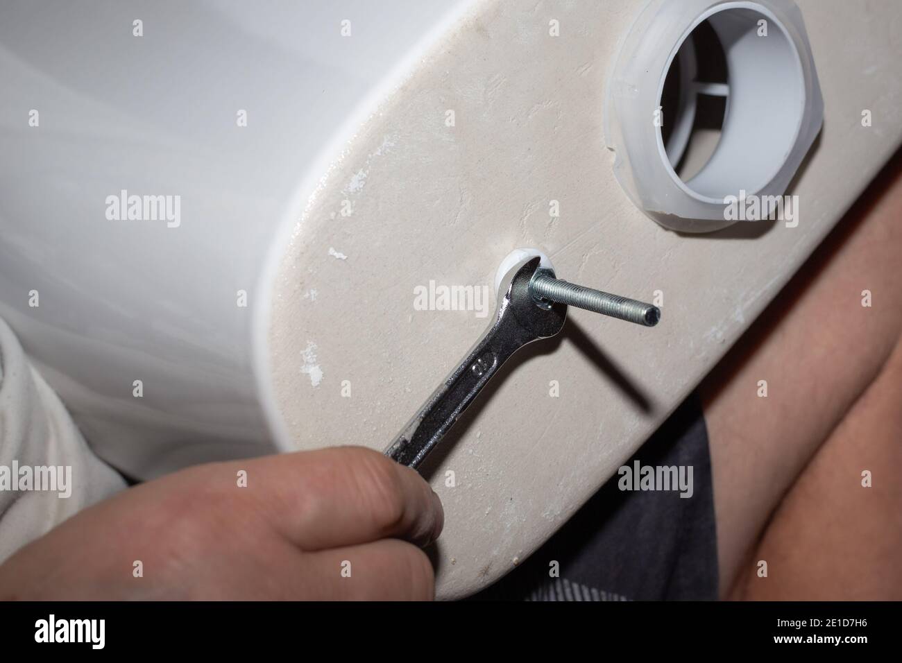 Assembly and installation of the toilet. A man with a wrench tightens ...