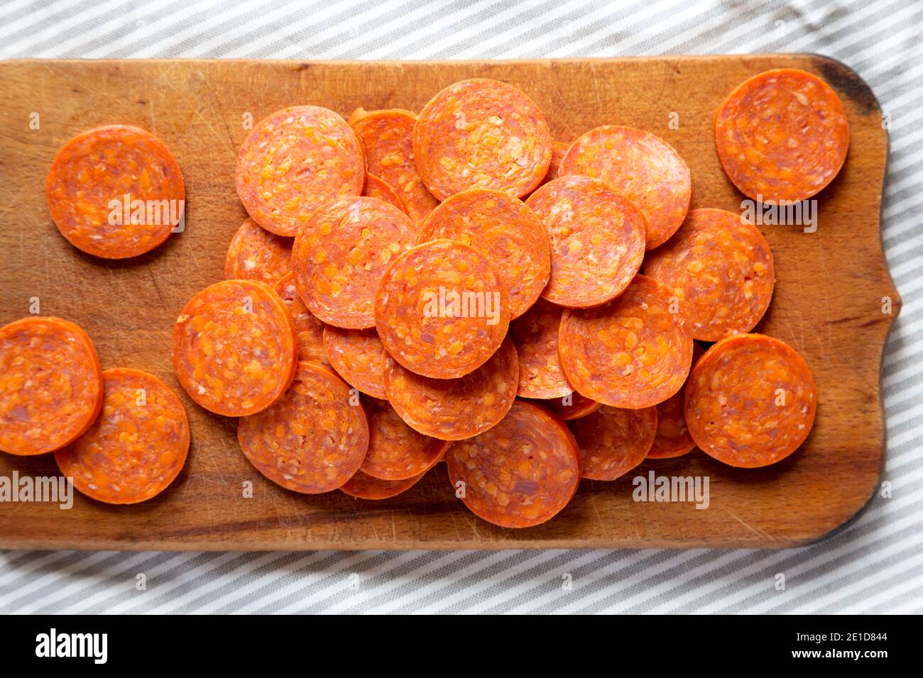 Italian Pepperoni Slices on a rustic wooden board on cloth, overhead ...