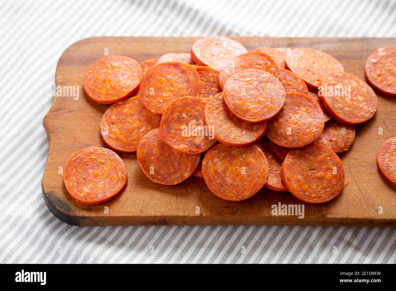 Italian Pepperoni Slices on a rustic wooden board on cloth, side view ...