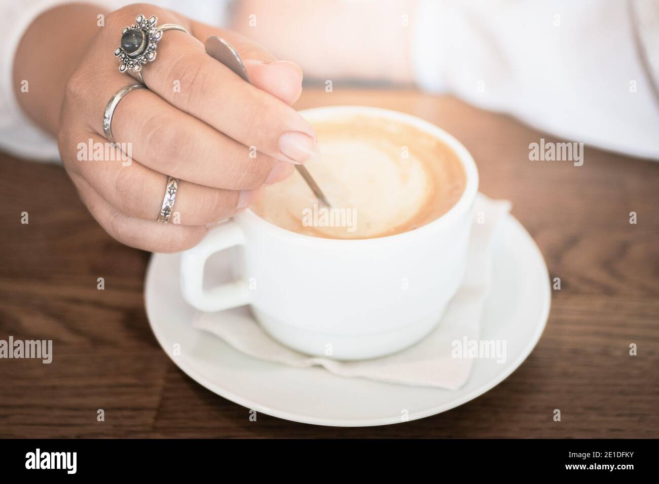 Coffee late in white cup and female hand with spoon, close up. Good ...