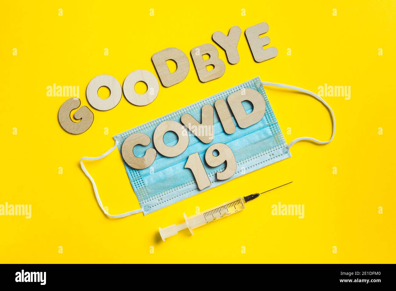 Words GOODBYE COVID 19 from wooden letters, syringe with vaccine on ...