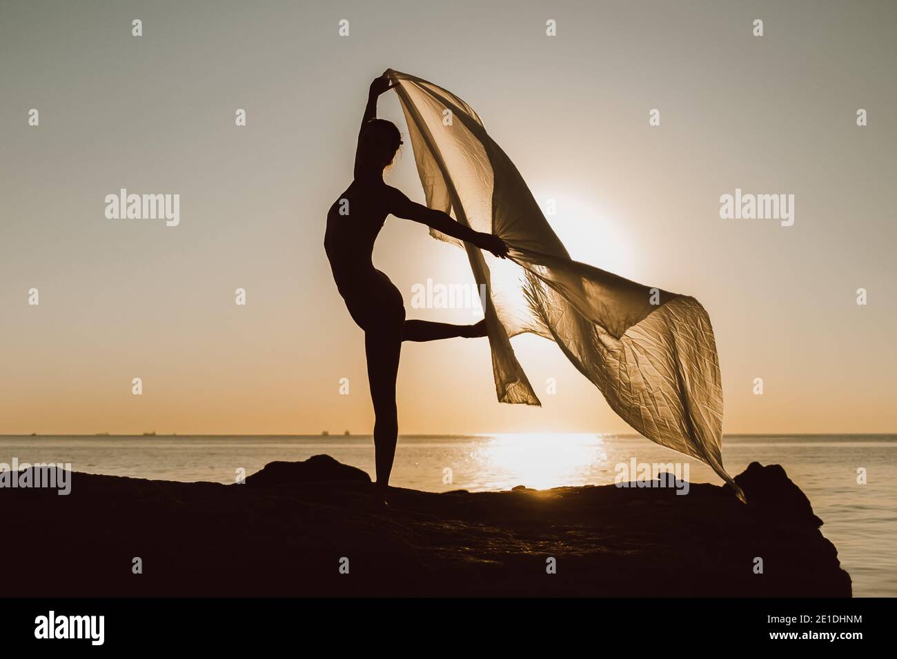 Young beautiful ballerina dancing ballet on sky and sea background with ...