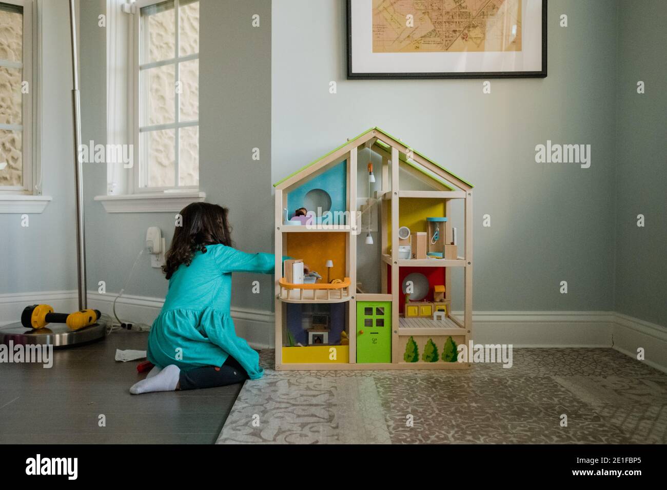 young girl playing with dollhouse in living room Stock Photo - Alamy