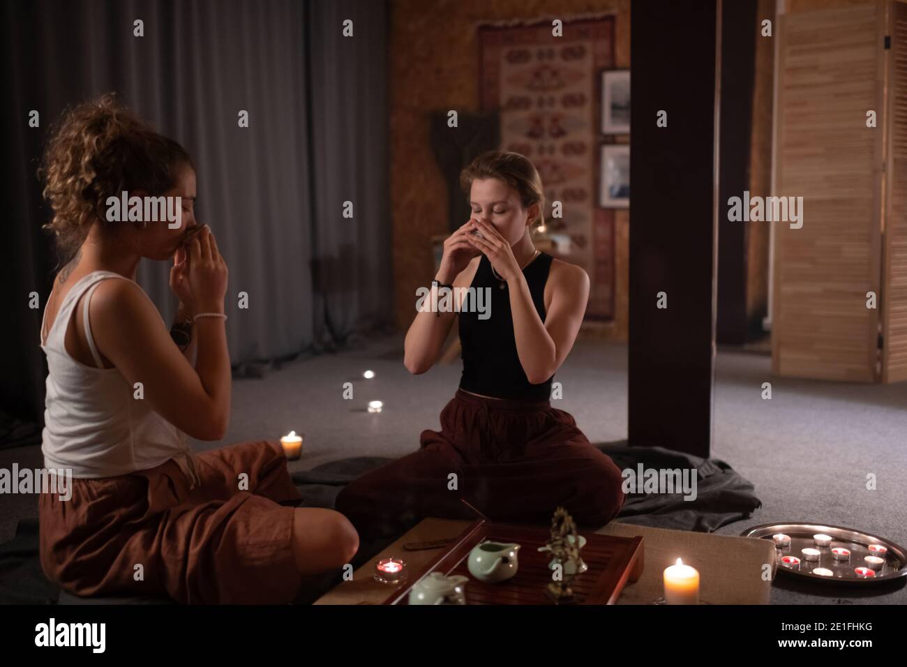 Young women sipping Asian tea with closed eyes during teatime in yoga ...