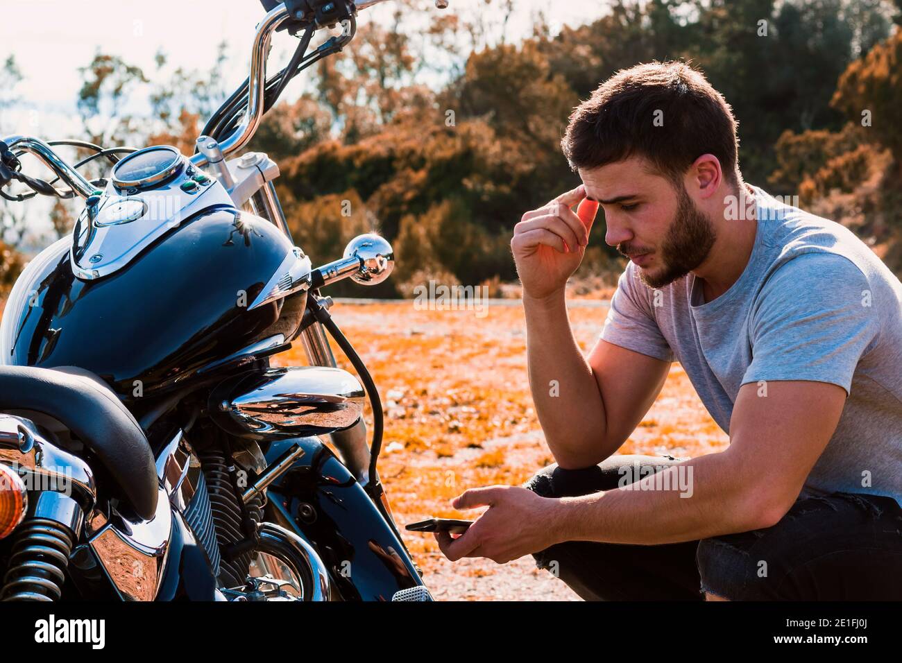 Crouching biker worried about a motorcycle breakdown Stock Photo - Alamy