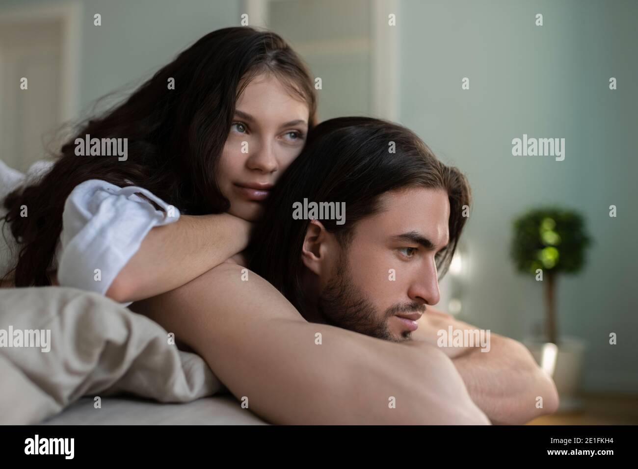 Young female resting on back of boyfriend while chilling on bed at home ...