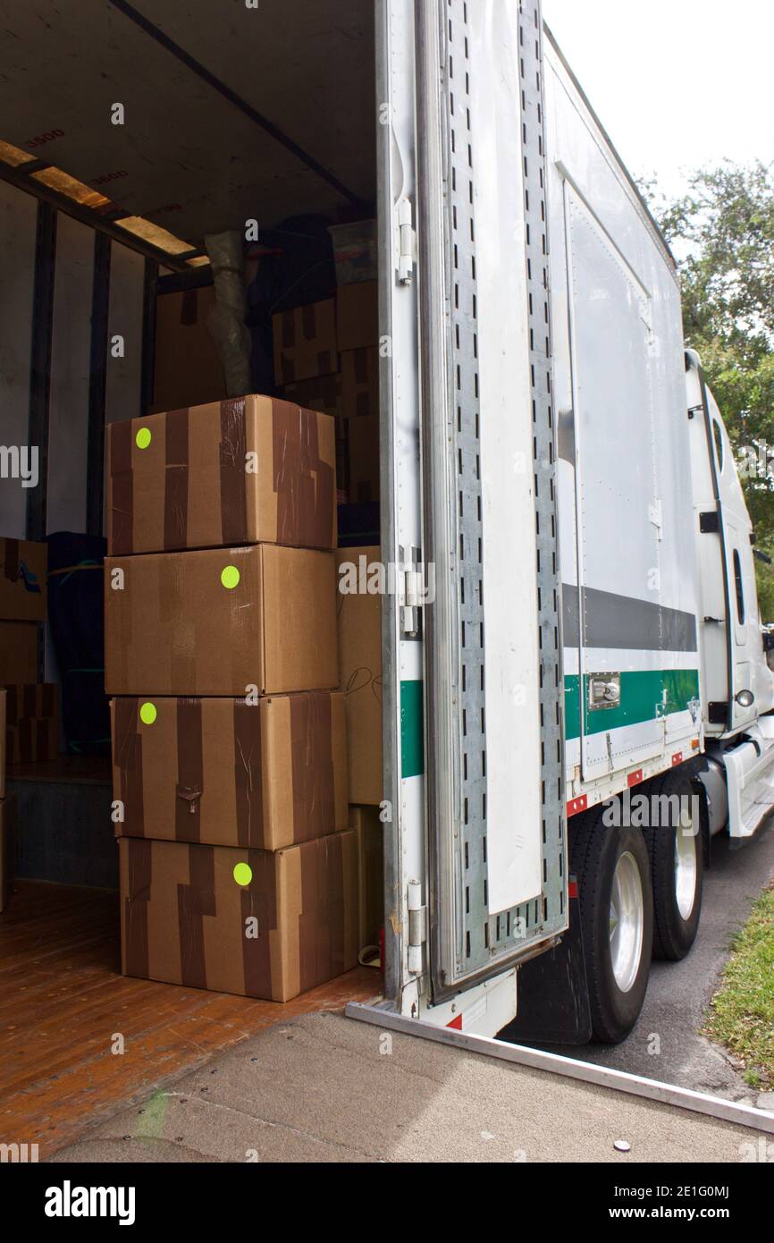 Moving van trailer with packed boxes by open door with bright labels or ...